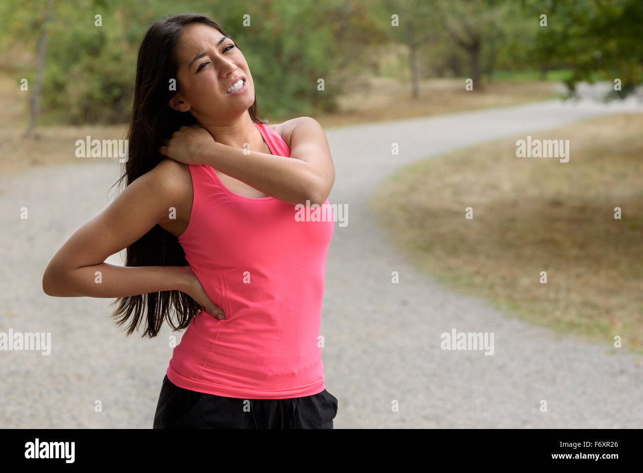 Young woman out jogging suffers a muscle injury standing holding her ...