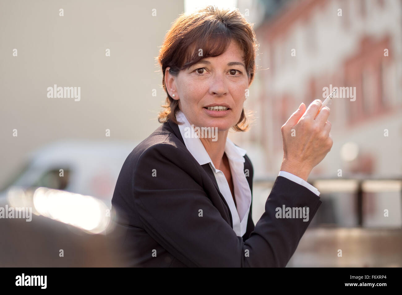 Attractive businesswoman taking a smoke break at the office standing ...