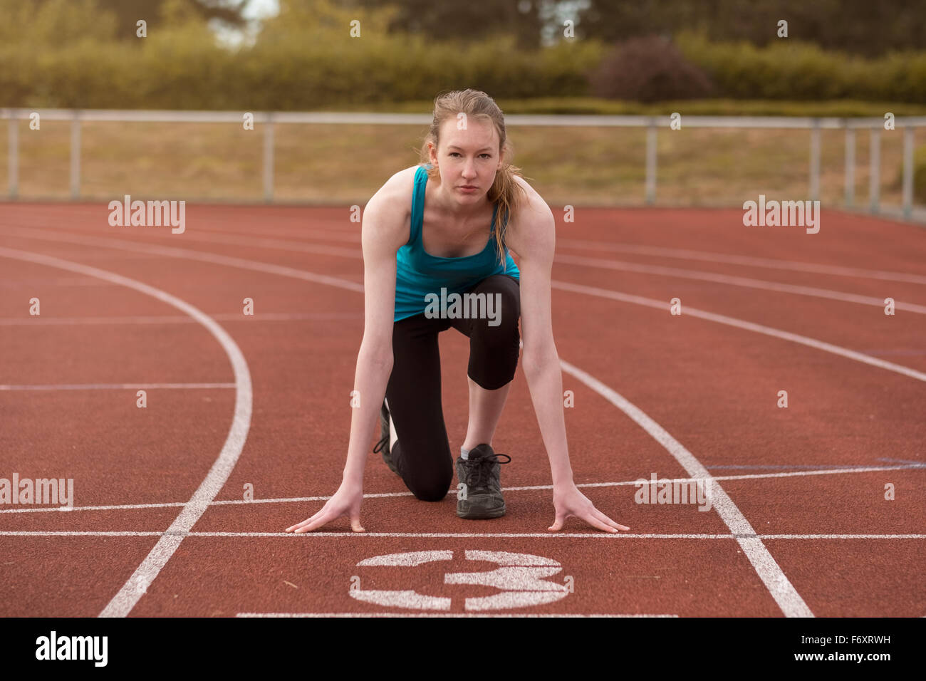Young woman sprinter in the starter position on a race track at a ...