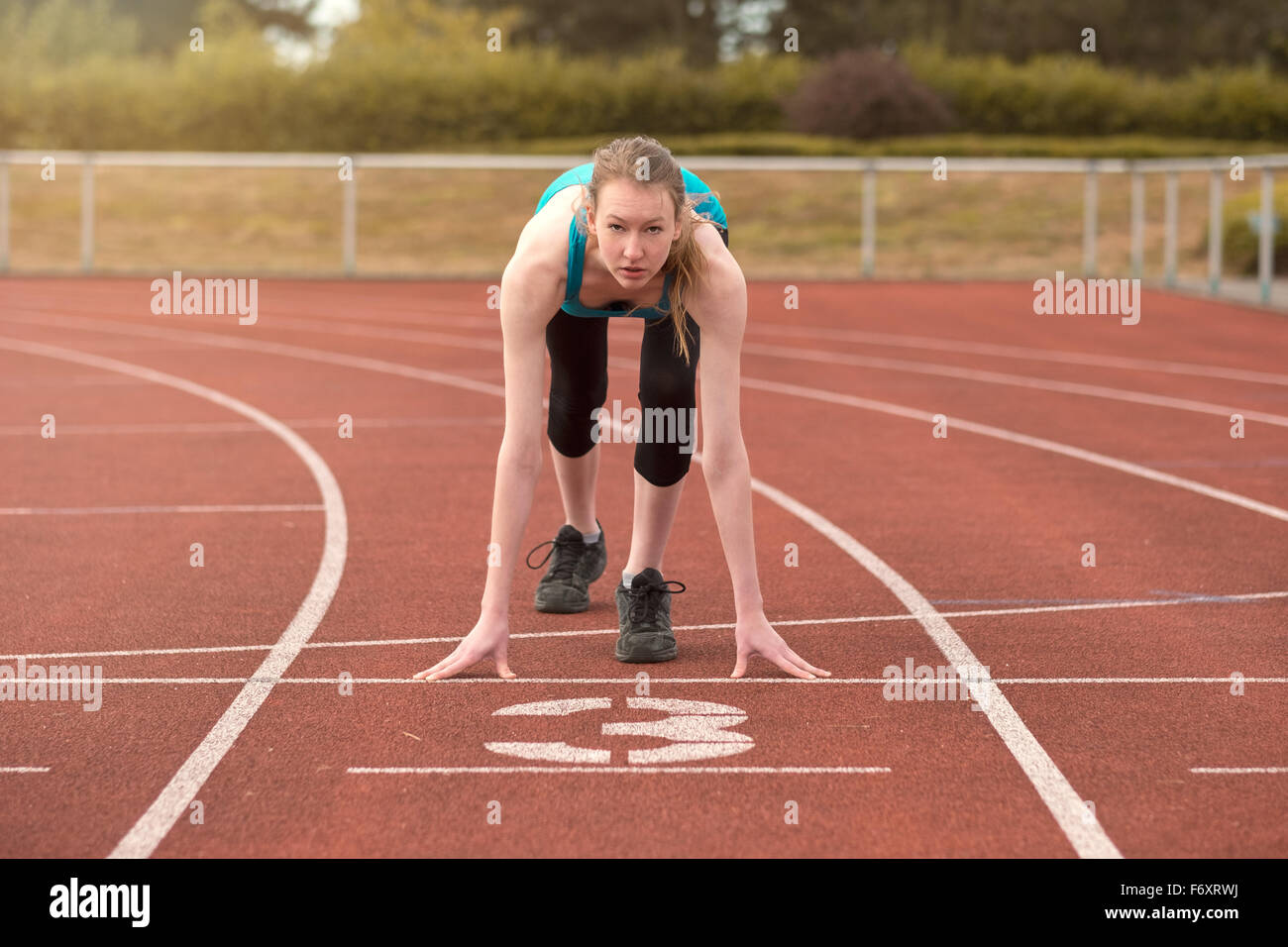 Young woman sprinter in the starter position on a race track at a ...