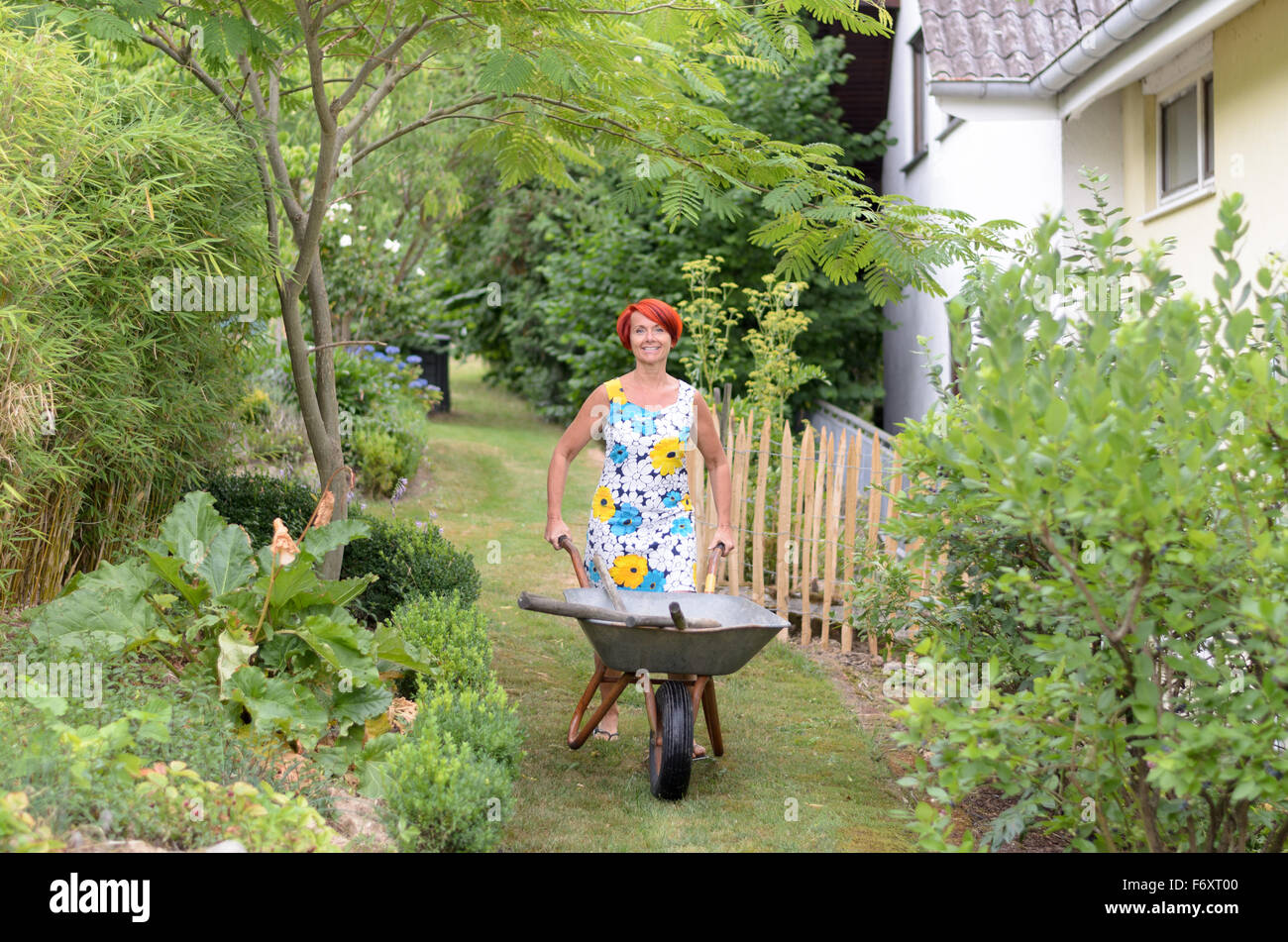 Happy Redhead Woman in Floral Dress, Pushing a Garden Wheelbarrow with ...