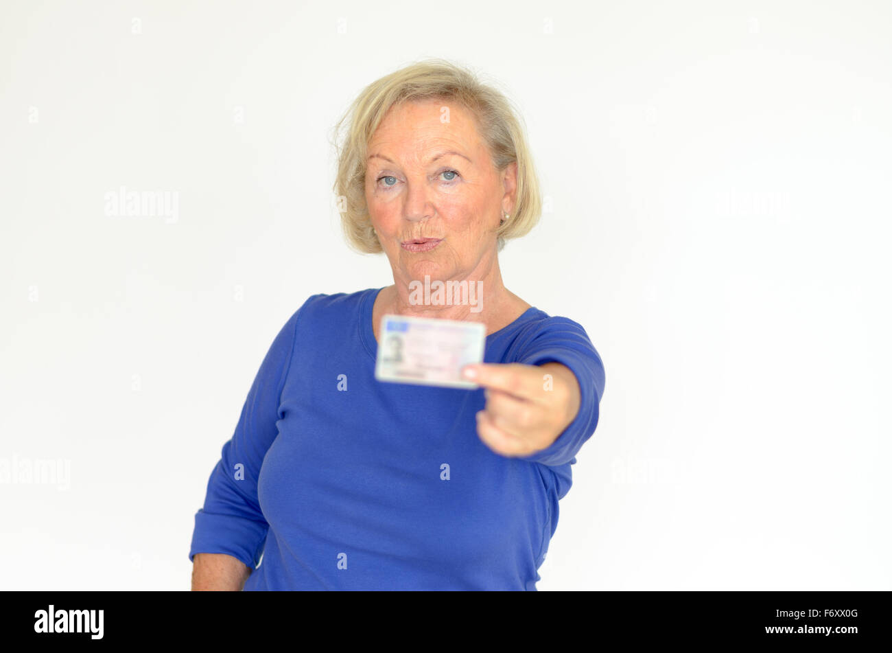 Senior lady holding out her driver´s license at arms length towards the ...