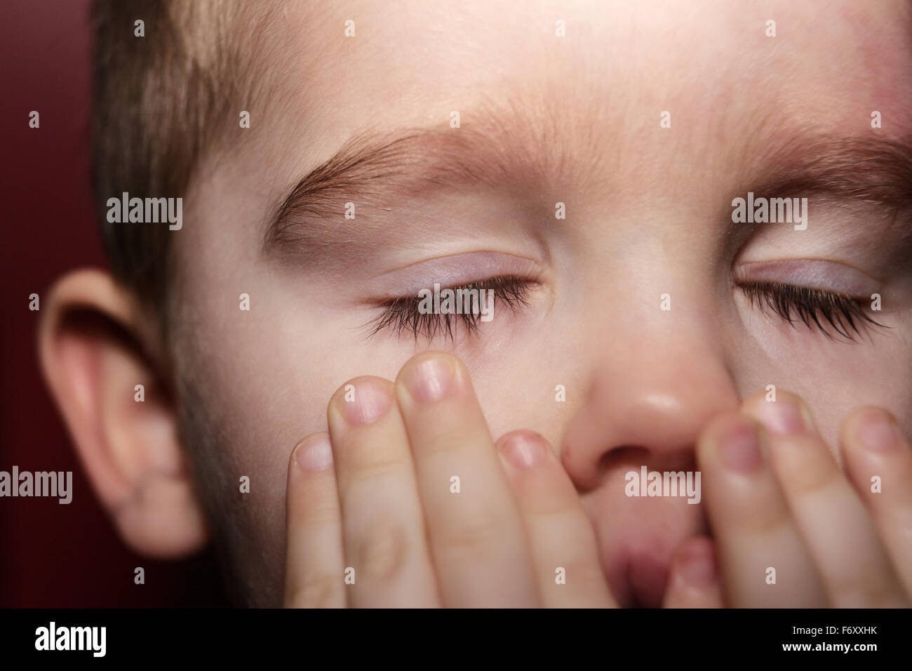 closer up shot of a young boys face not looking happy pulling his eye ...
