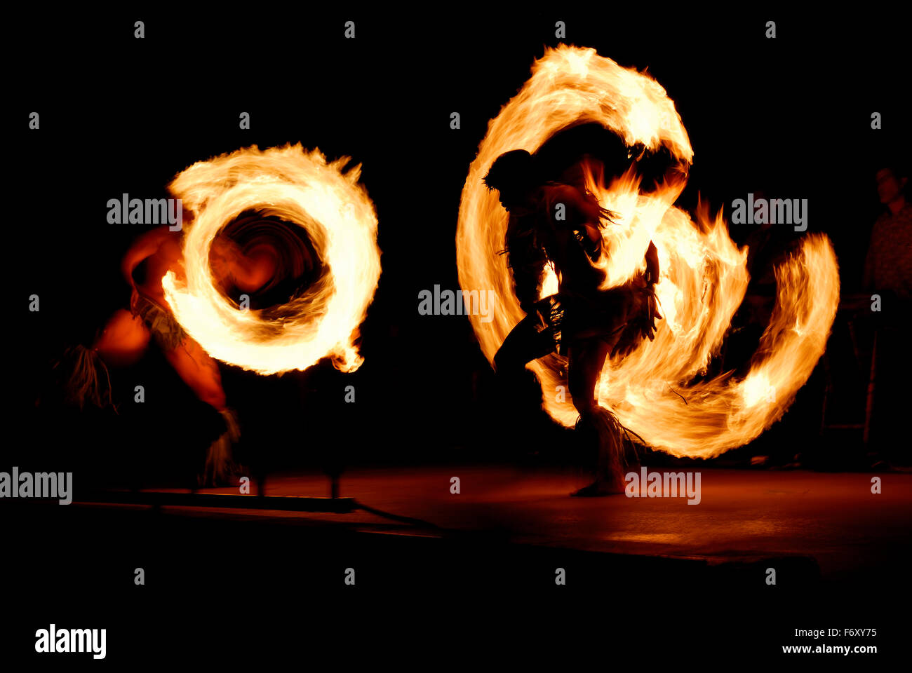 Pair of competing fire dancers spinning lit batons at night after a ...