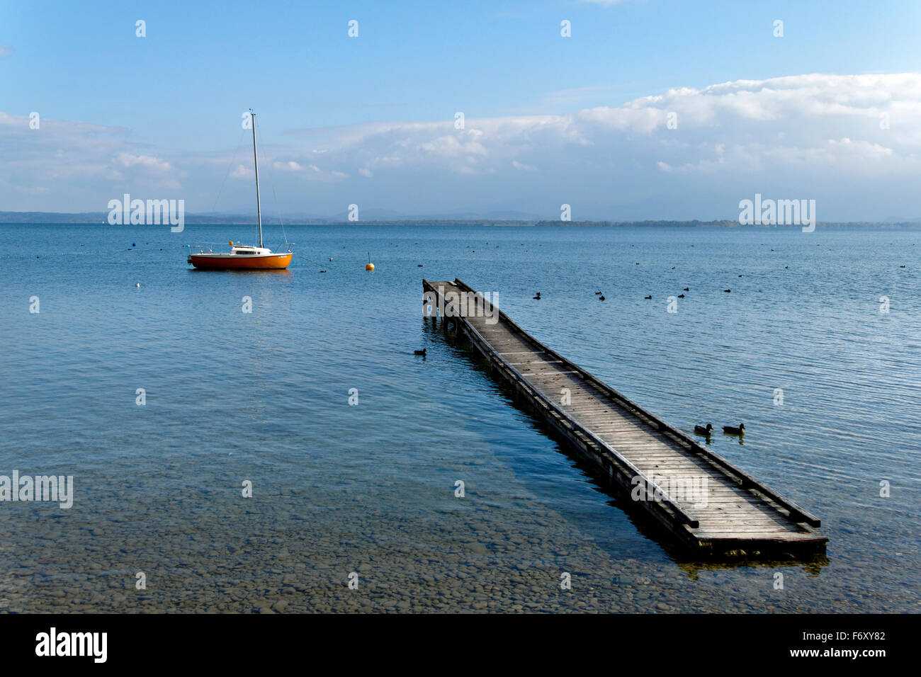 Lake Chiemsee beach foreshore with small boats and pier, Chiemgau ...