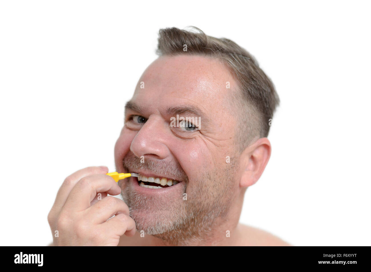 Middle aged man using interdental brush, head looking at the camera ...