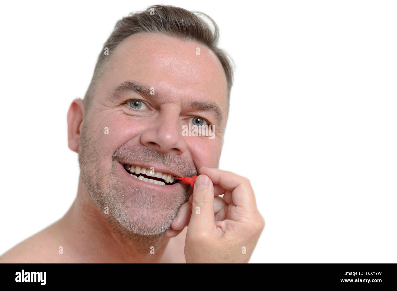 Middle aged man using interdental brush, head looking at the camera ...