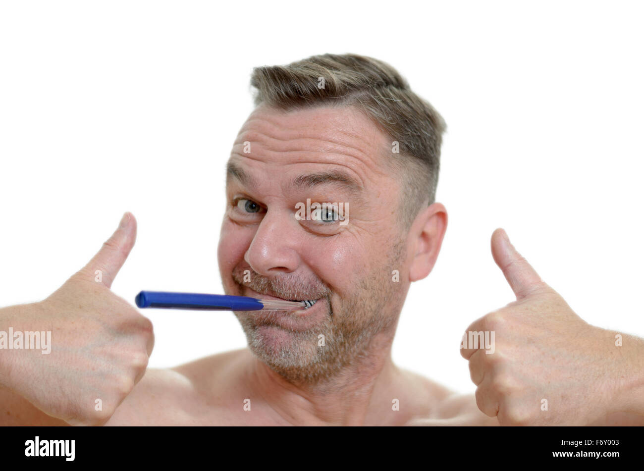 Charismatic man cleaning his teeth looking at the camera with a comic ...
