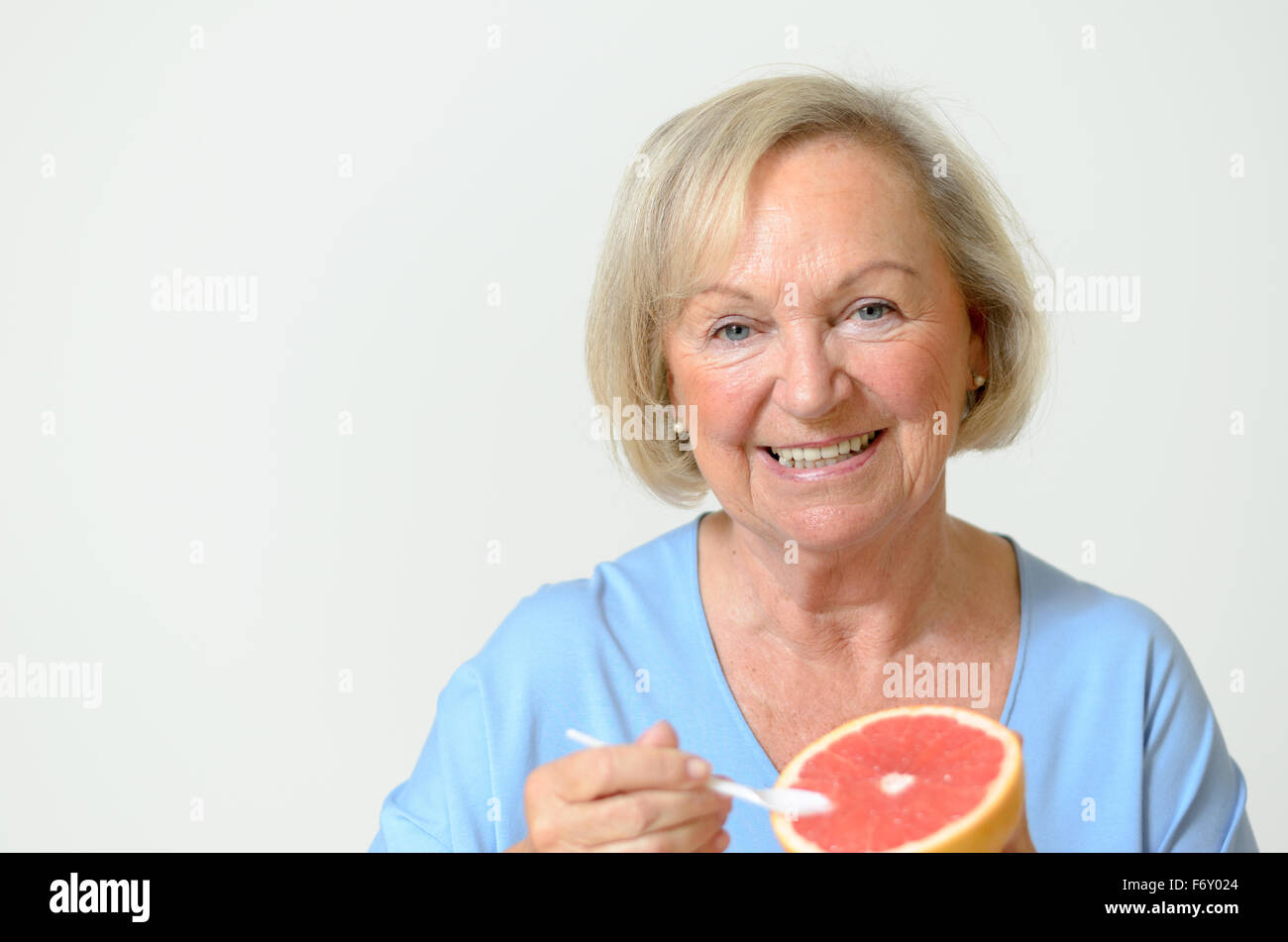 Happy friendly smiling senior lady with a fresh healthy red grapefruit ...
