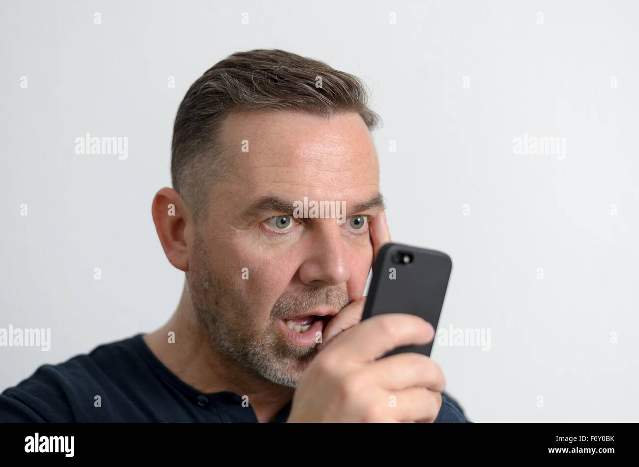 Surprised man looking at his mobile phone Stock Photo - Alamy
