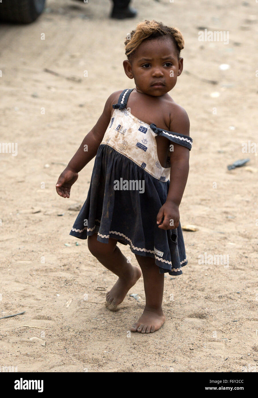 A young girl walks across a dusty street in the Garden Compound ...