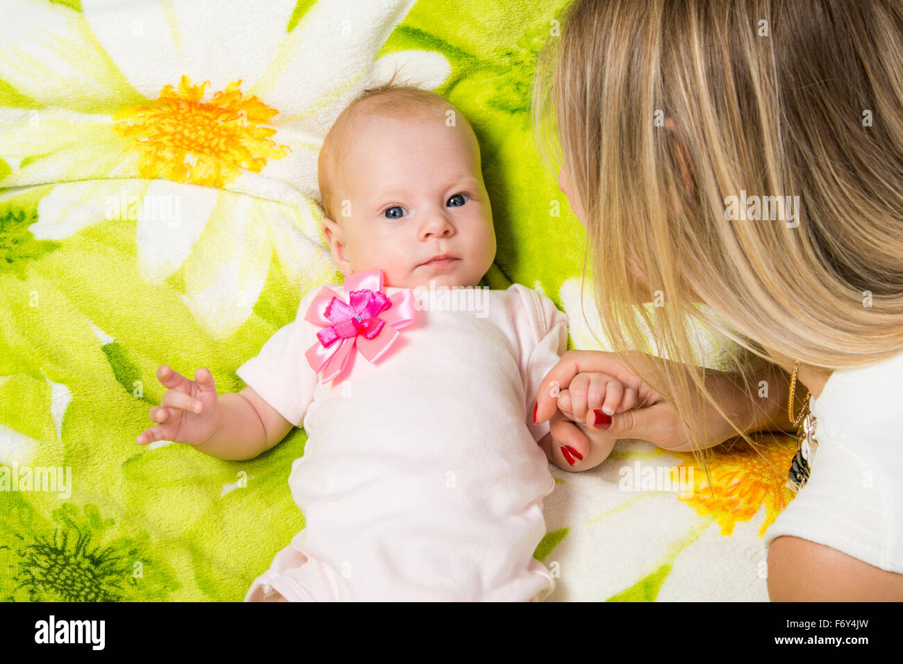 a two-month baby lying on his back on the bed, sitting next to the ...