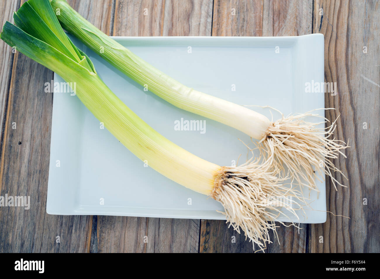 leeks on wooden table Stock Photo - Alamy