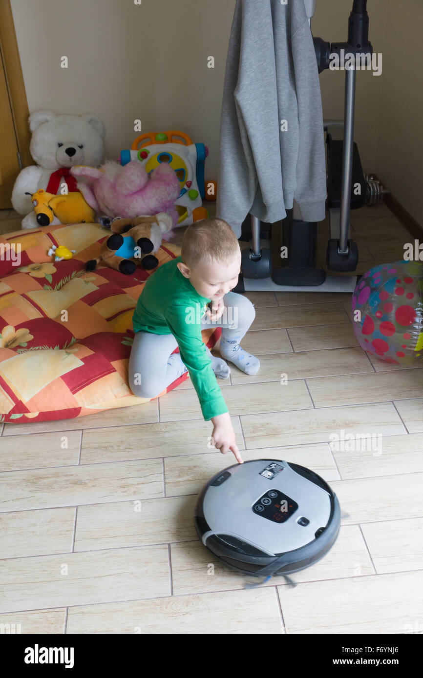 the little boy watches the robot the vacuum cleaner Stock Photo - Alamy