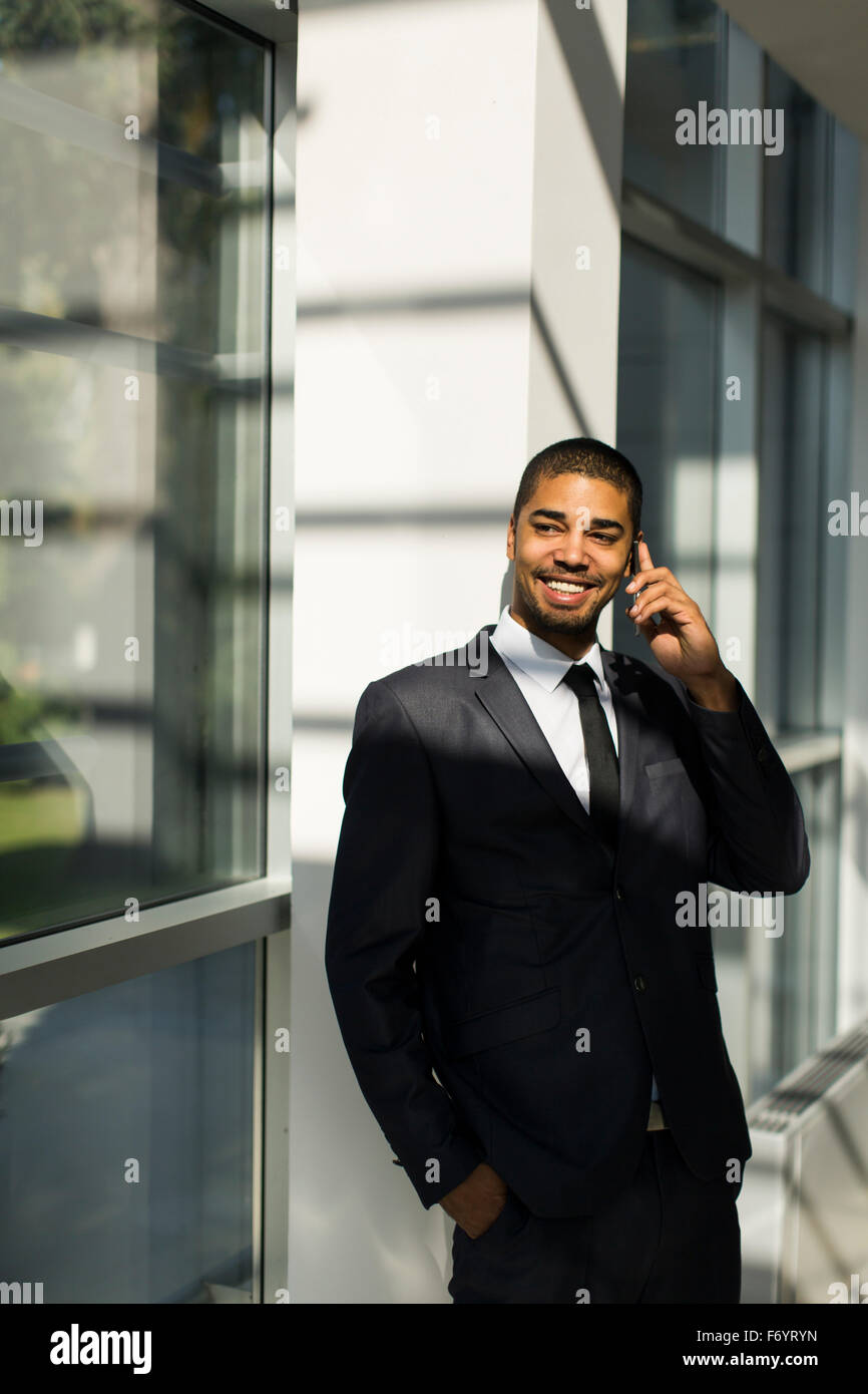 Handsome young black man with mobile phone in the office Stock Photo - Alamy