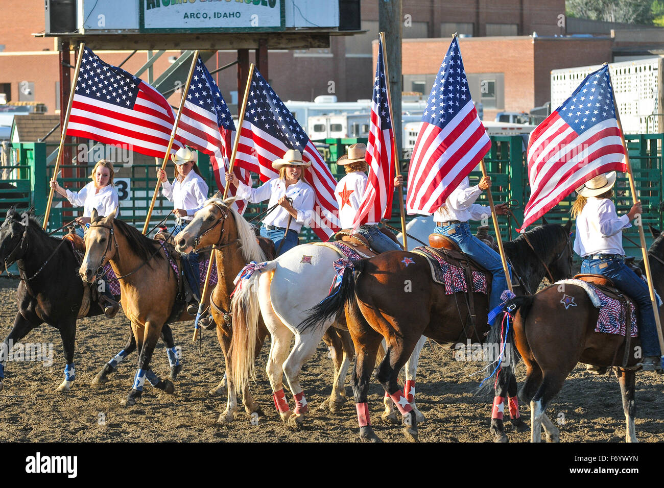 Cow girls bearing the flag of America while horseback riding in ...