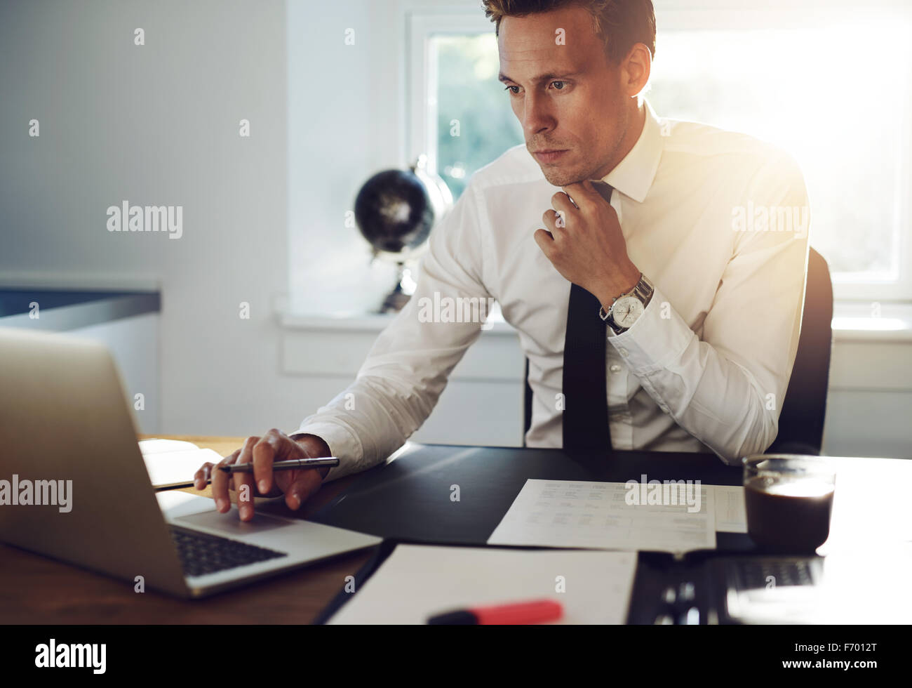 Business man sitting at his desk working on a computer and looking ...