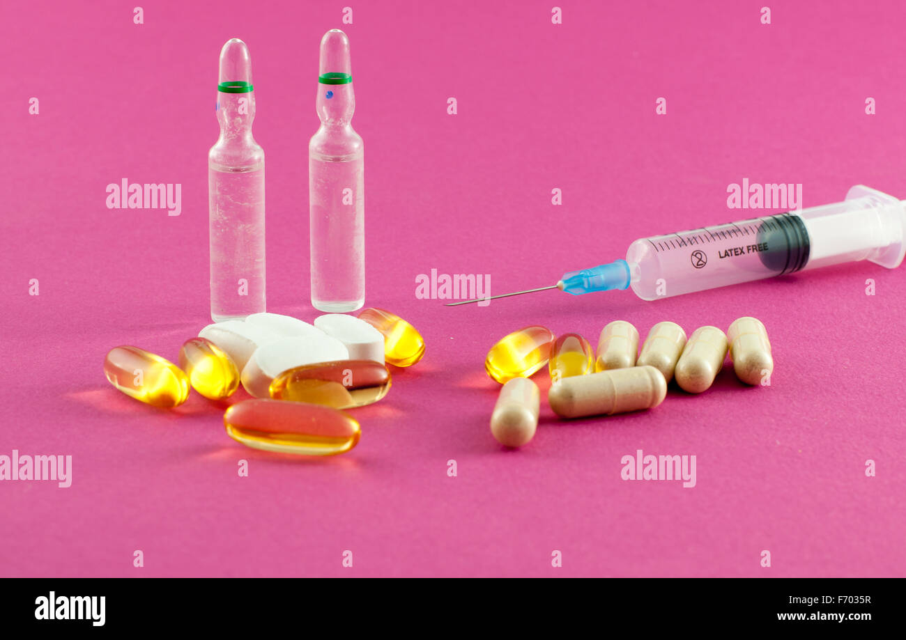 Phials, pills and syringe on pink background Stock Photo - Alamy