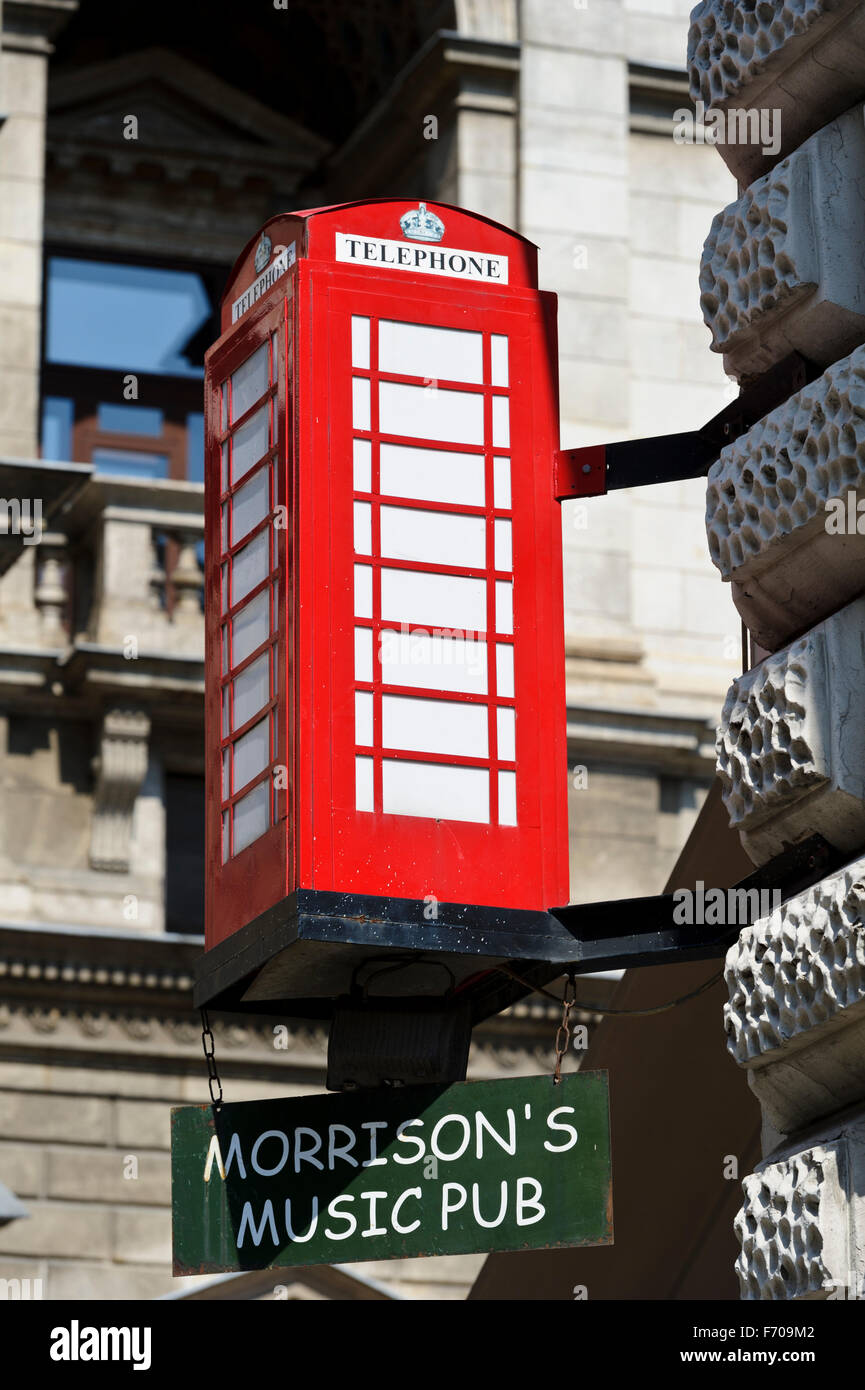 A small British red telephone box hanging on the outside wall of a ...