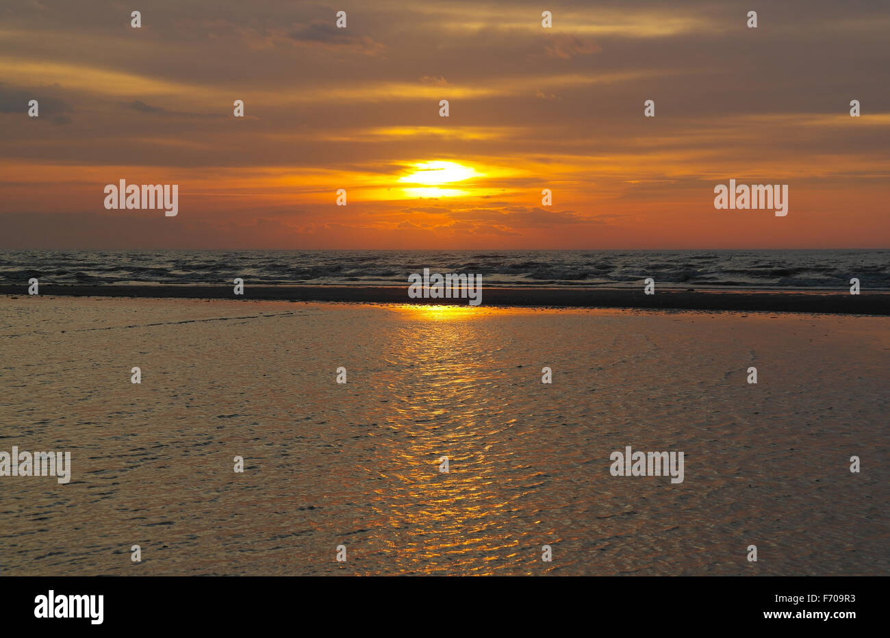 Beach view with large sea water pool towards yellow red sun sinking ...