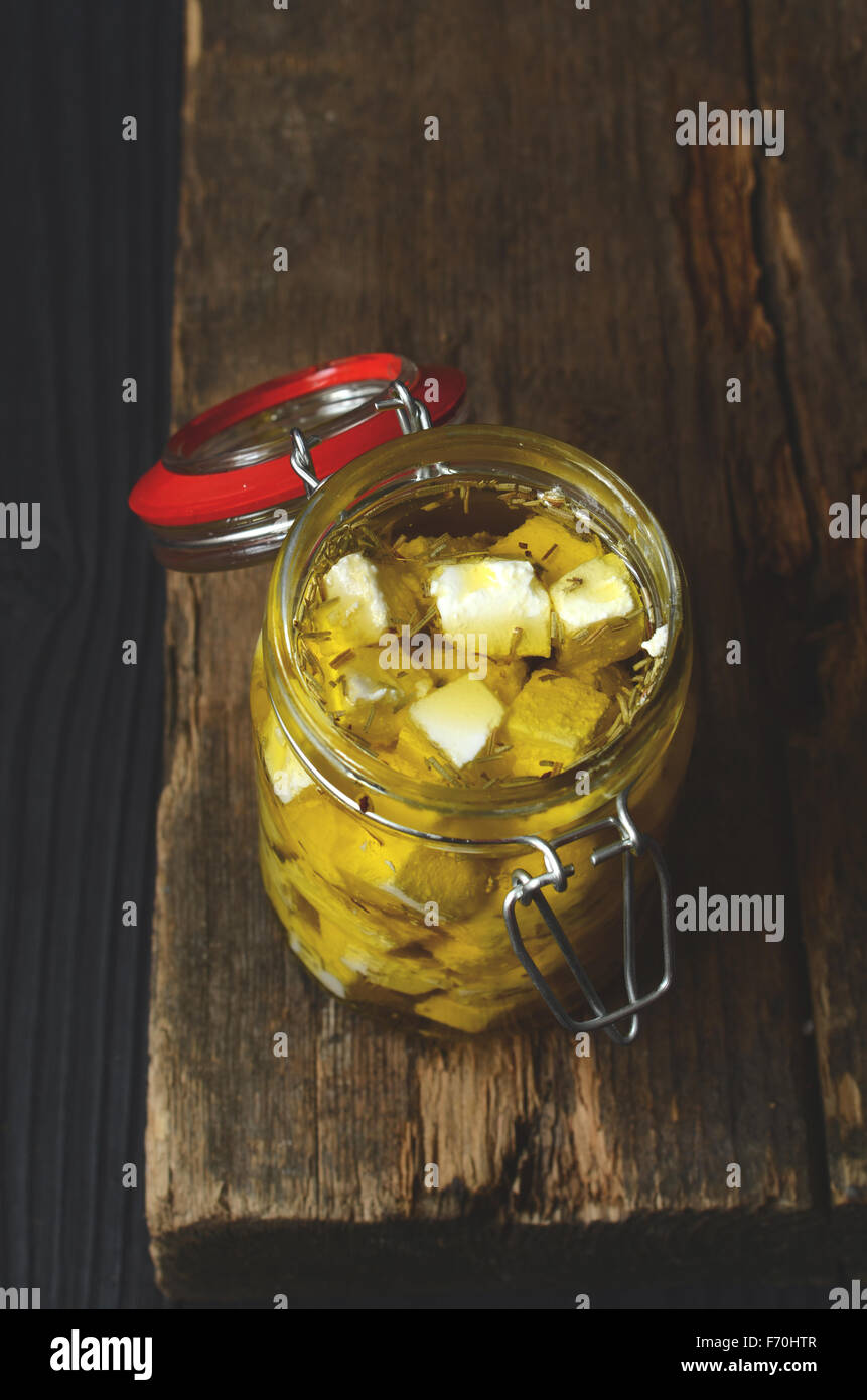 Feta cheese marinated with herbs and spices in olive oil in a glass jar ...