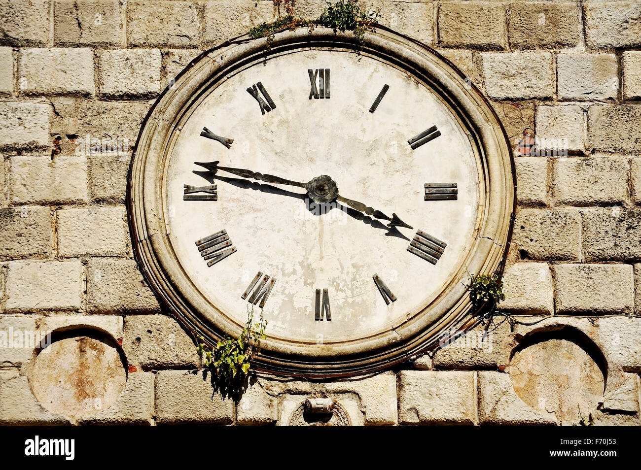 Old clock tower with vegetation growing on it in Kotor Stock Photo - Alamy
