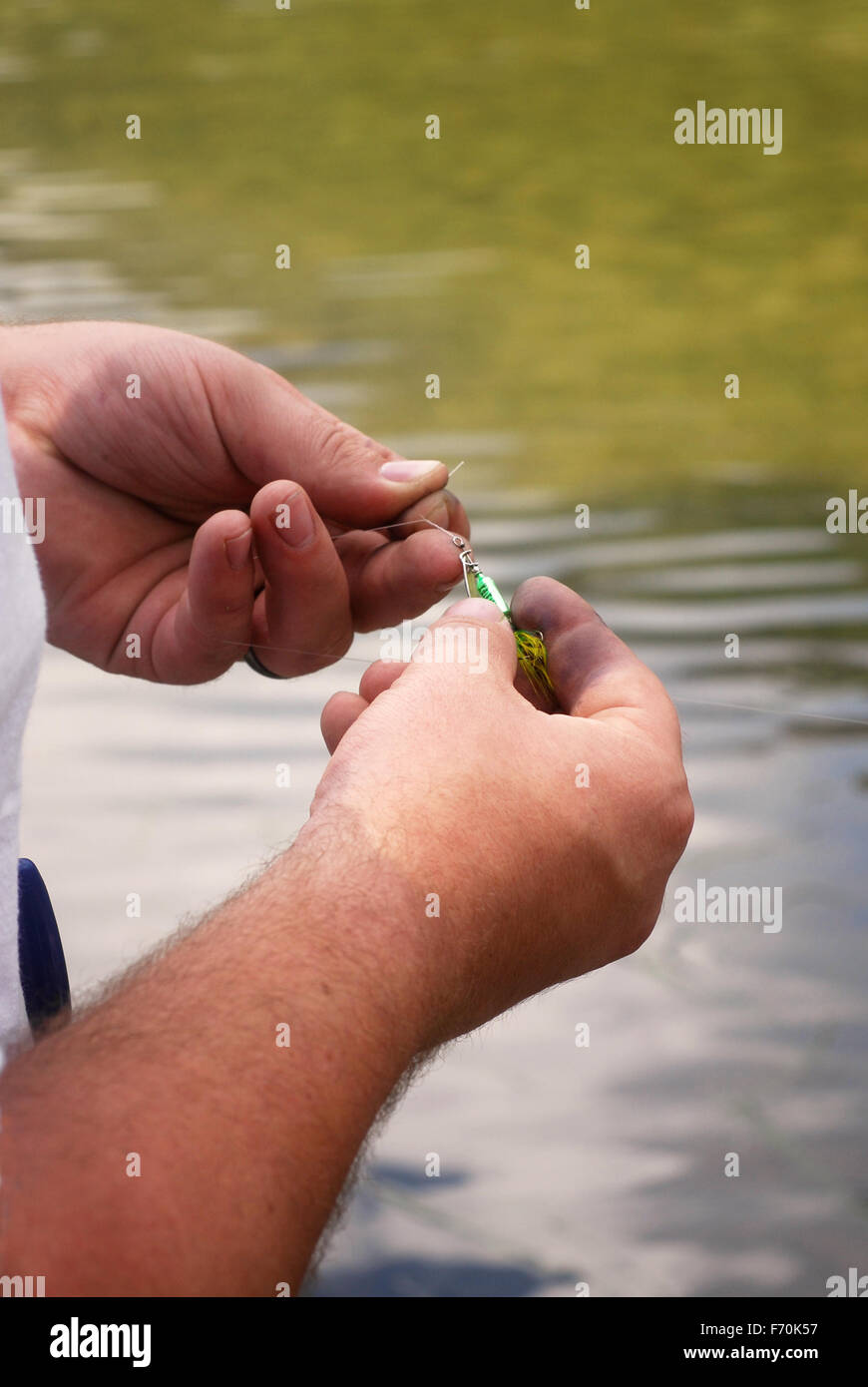 Man tying lure to fishing line Stock Photo - Alamy