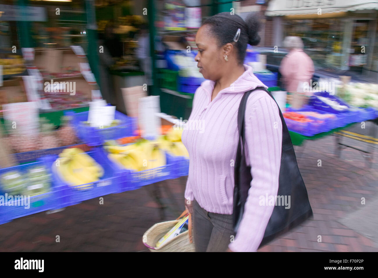 Woman out shopping passing a green grocers store Stock Photo - Alamy