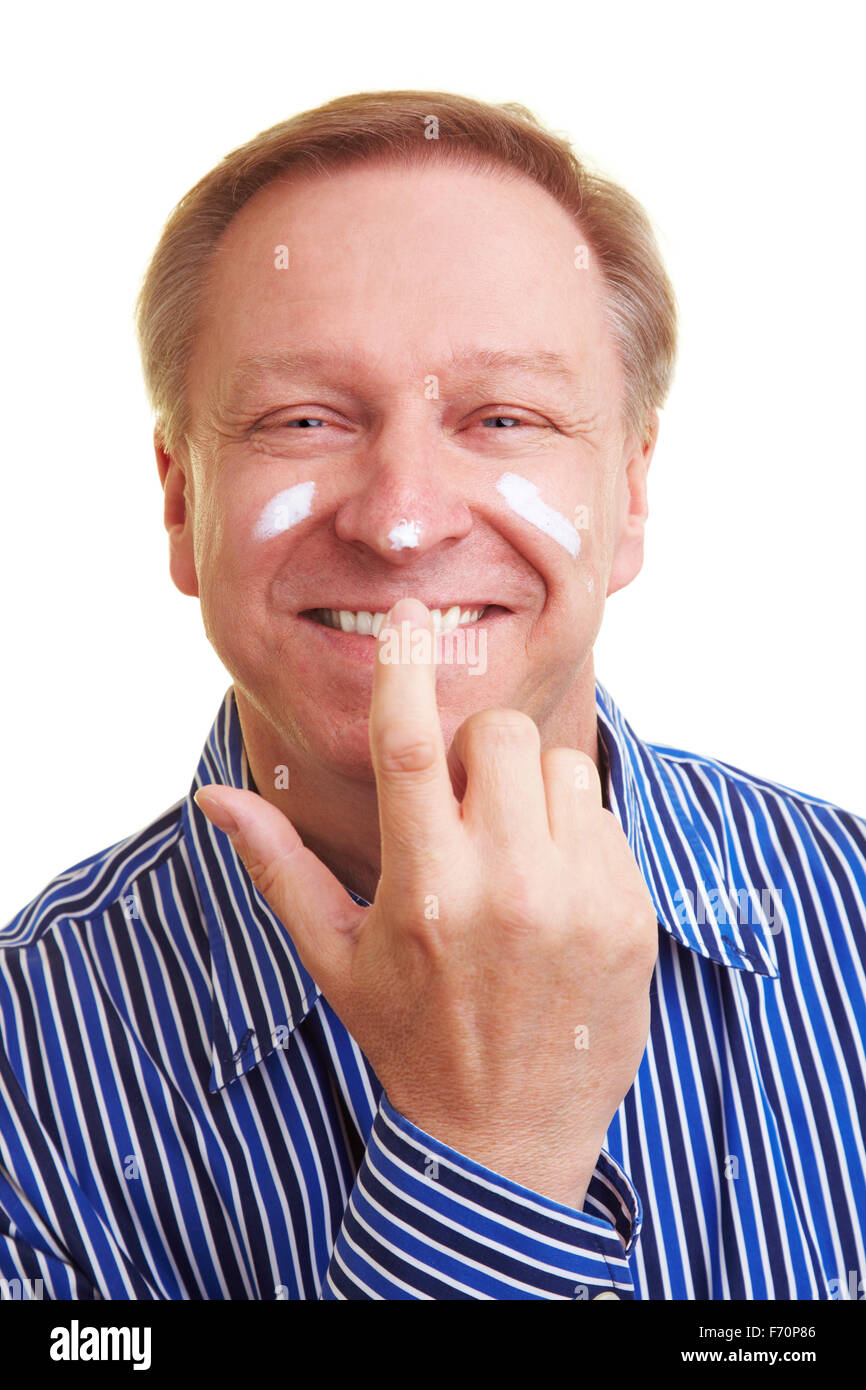 Smiling elderly man putting blob of lotion on his nose Stock Photo - Alamy