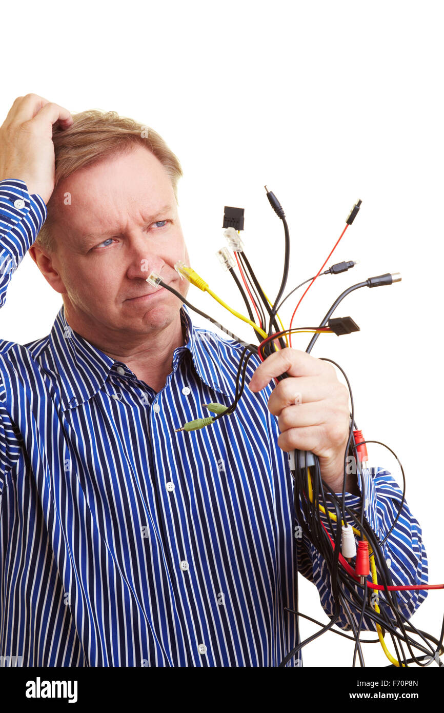 Elderly man with many different cables in his hand looking perplexed ...
