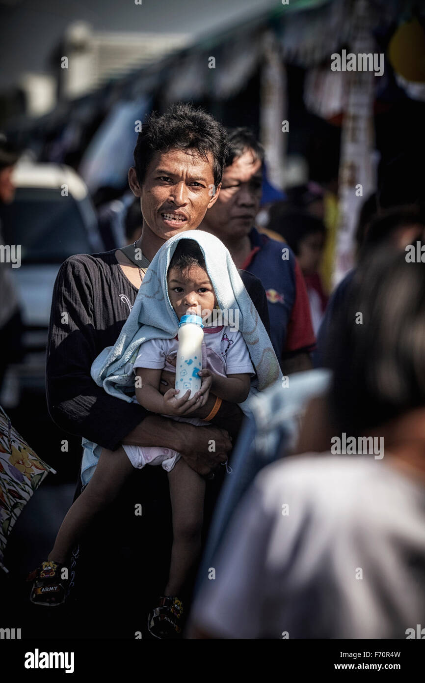 Man carrying baby. Father carrying his infant child through a crowded ...