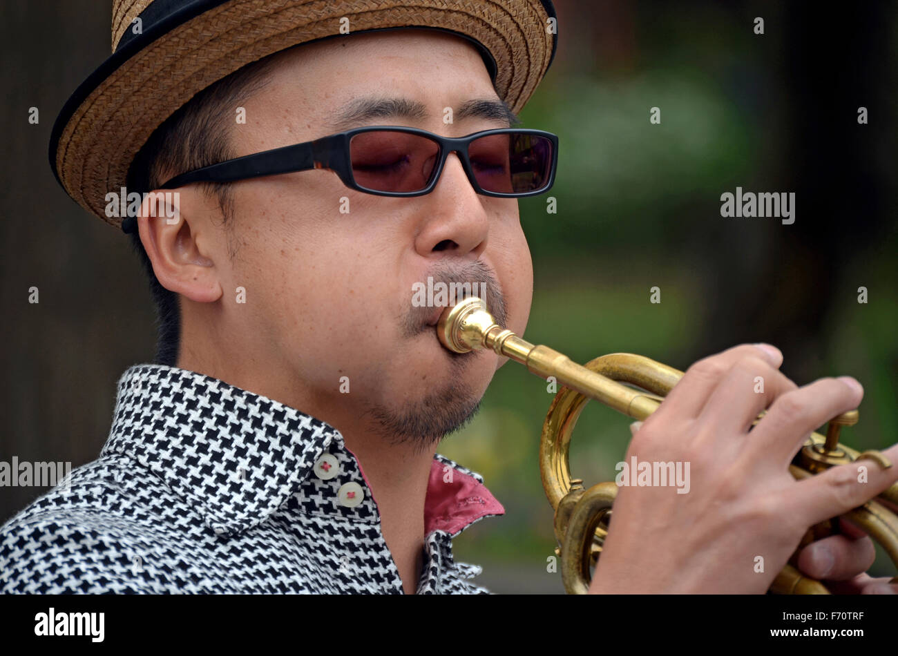 Close up portrait of an Asian trumpet player in Washington Square Park ...