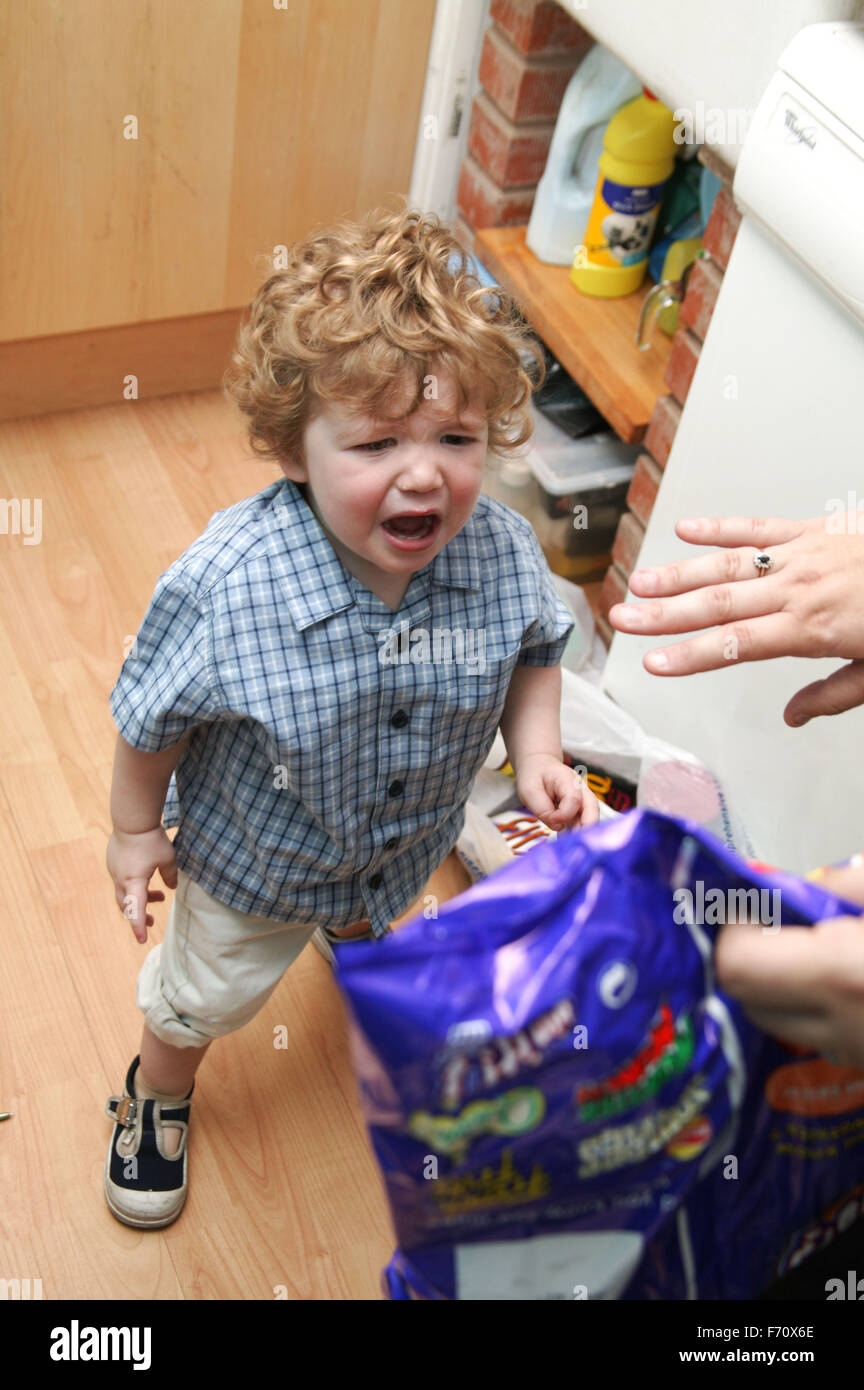 Toddler having a temper tantrum after being refused a packet of crisps ...