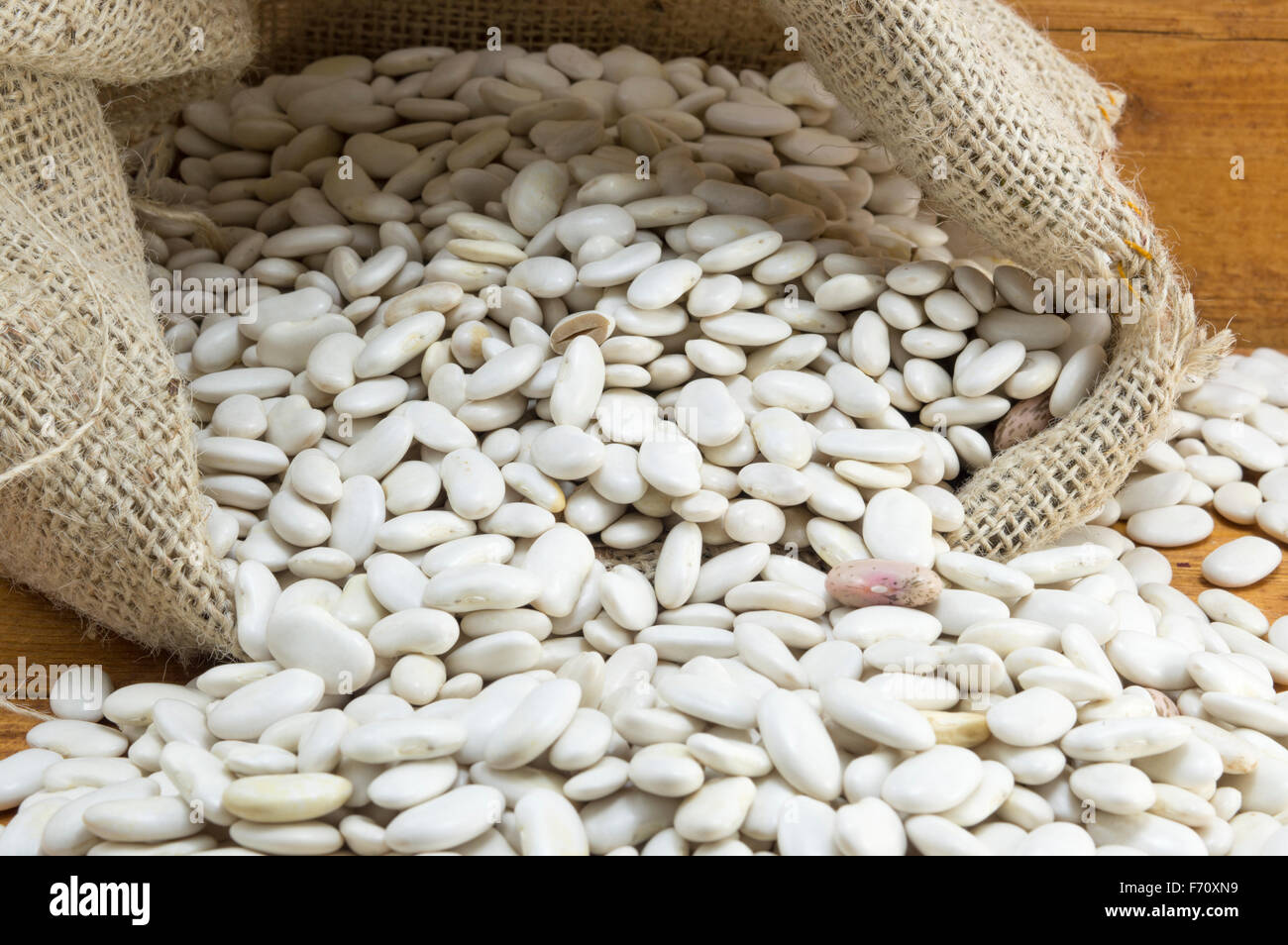 Natural white beans in a bag on a wooden table Stock Photo - Alamy
