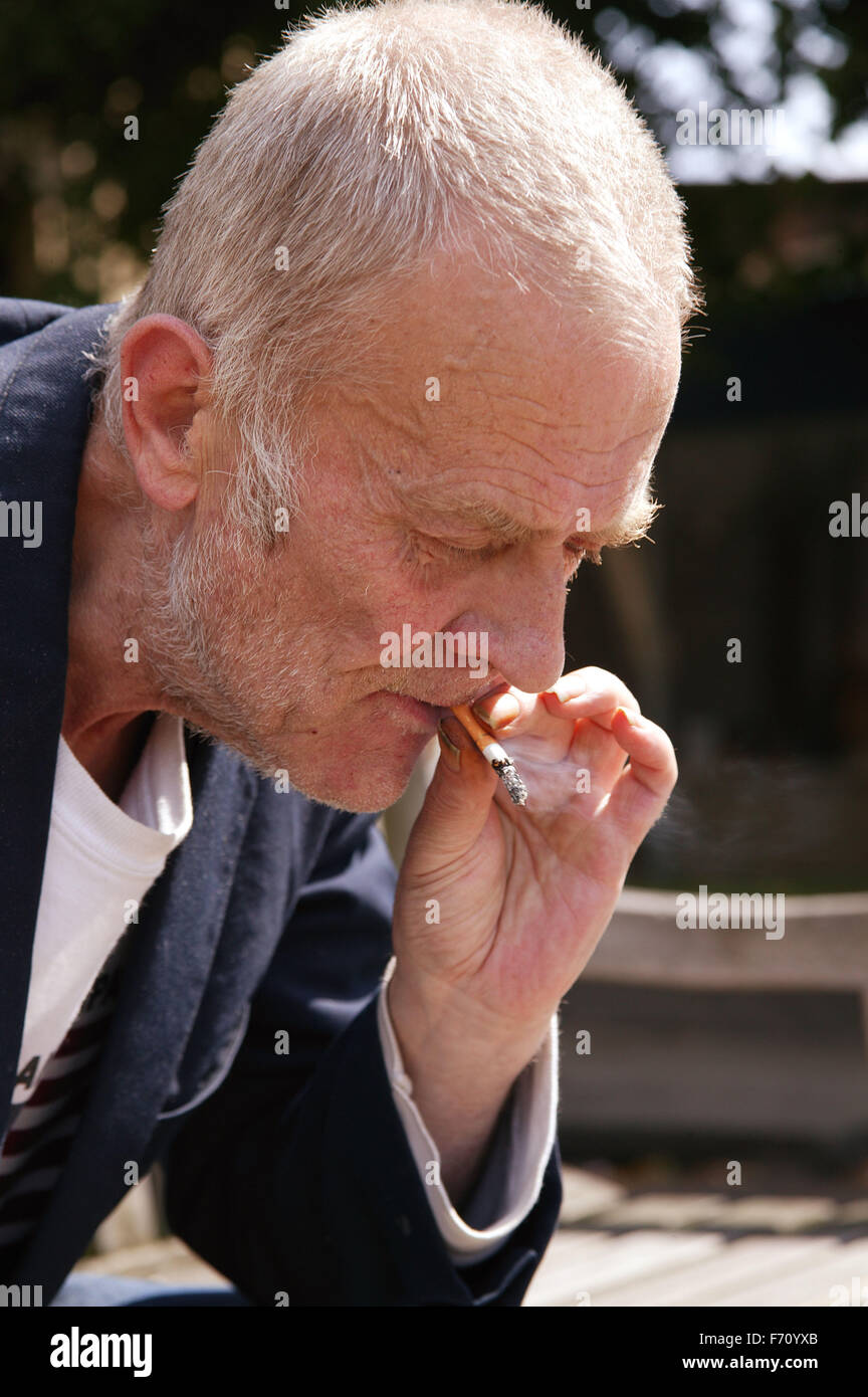 Man sitting on a bench smoking; Community Care Project user Stock Photo ...