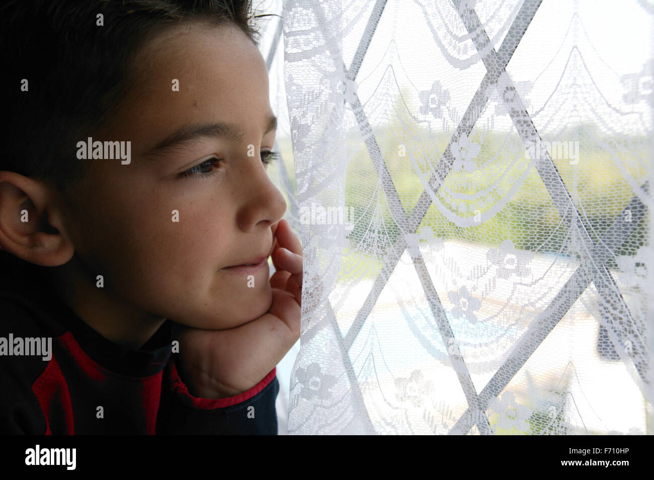Young boy looking out of window Stock Photo - Alamy