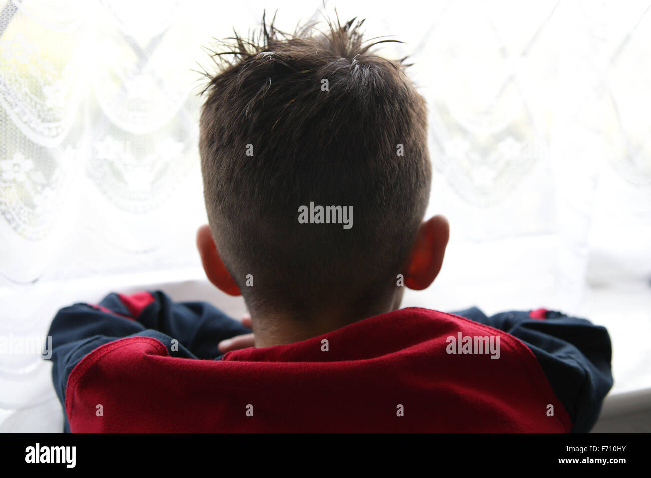 Young boy looking out of window Stock Photo - Alamy