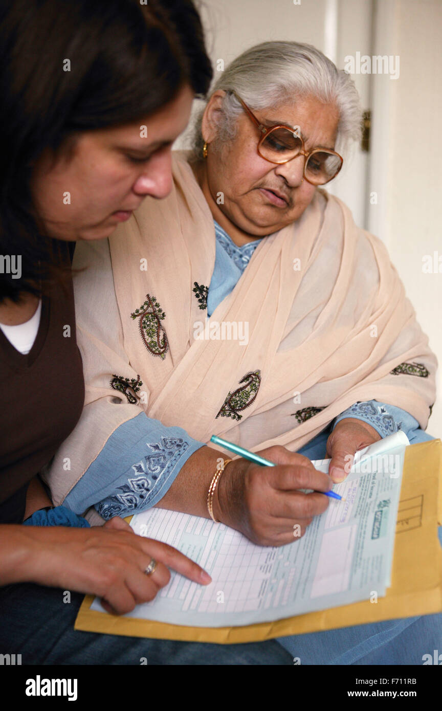 Community support worker helping South Asian lady fill in a form Stock ...