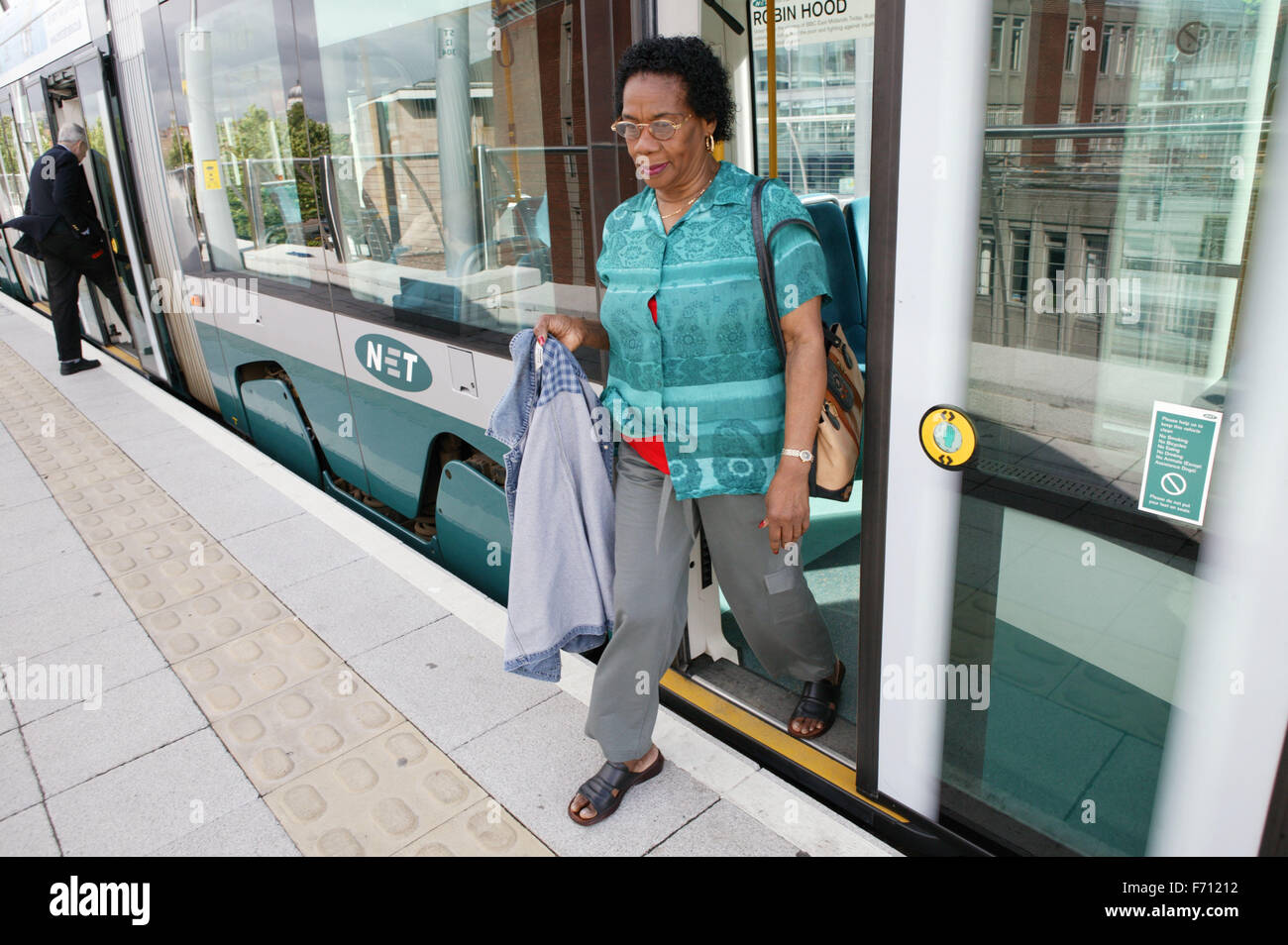 Woman stepping off a tram onto the platform Stock Photo - Alamy