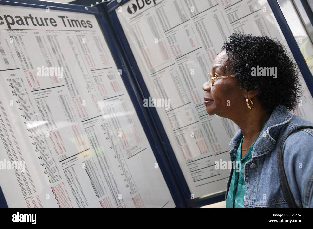Woman looking at train timetable at railway station Stock Photo - Alamy