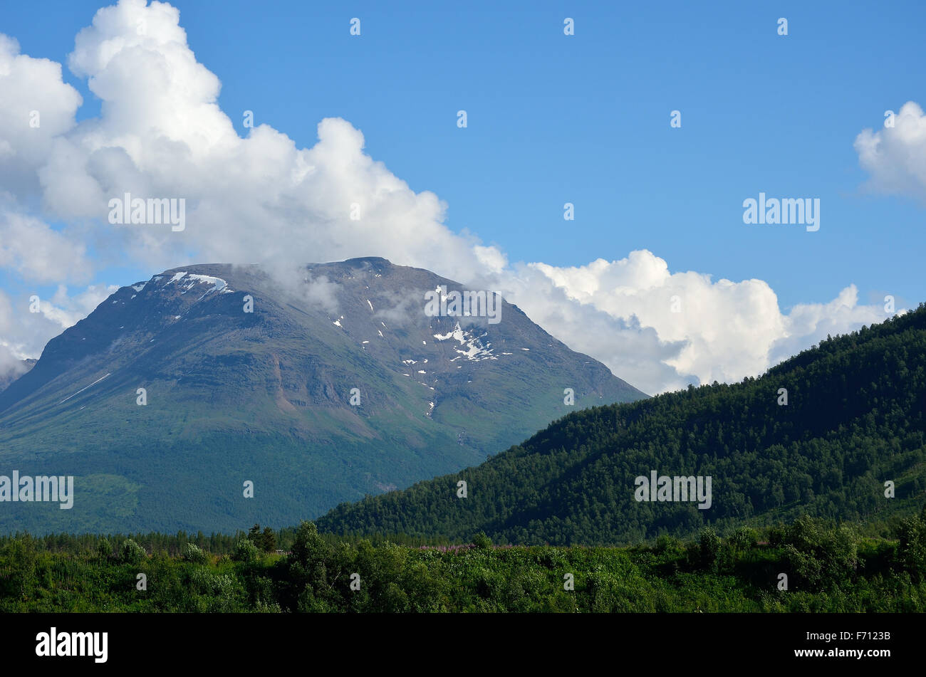 tall majestic mountain surrounded by small floating clouds in summer ...