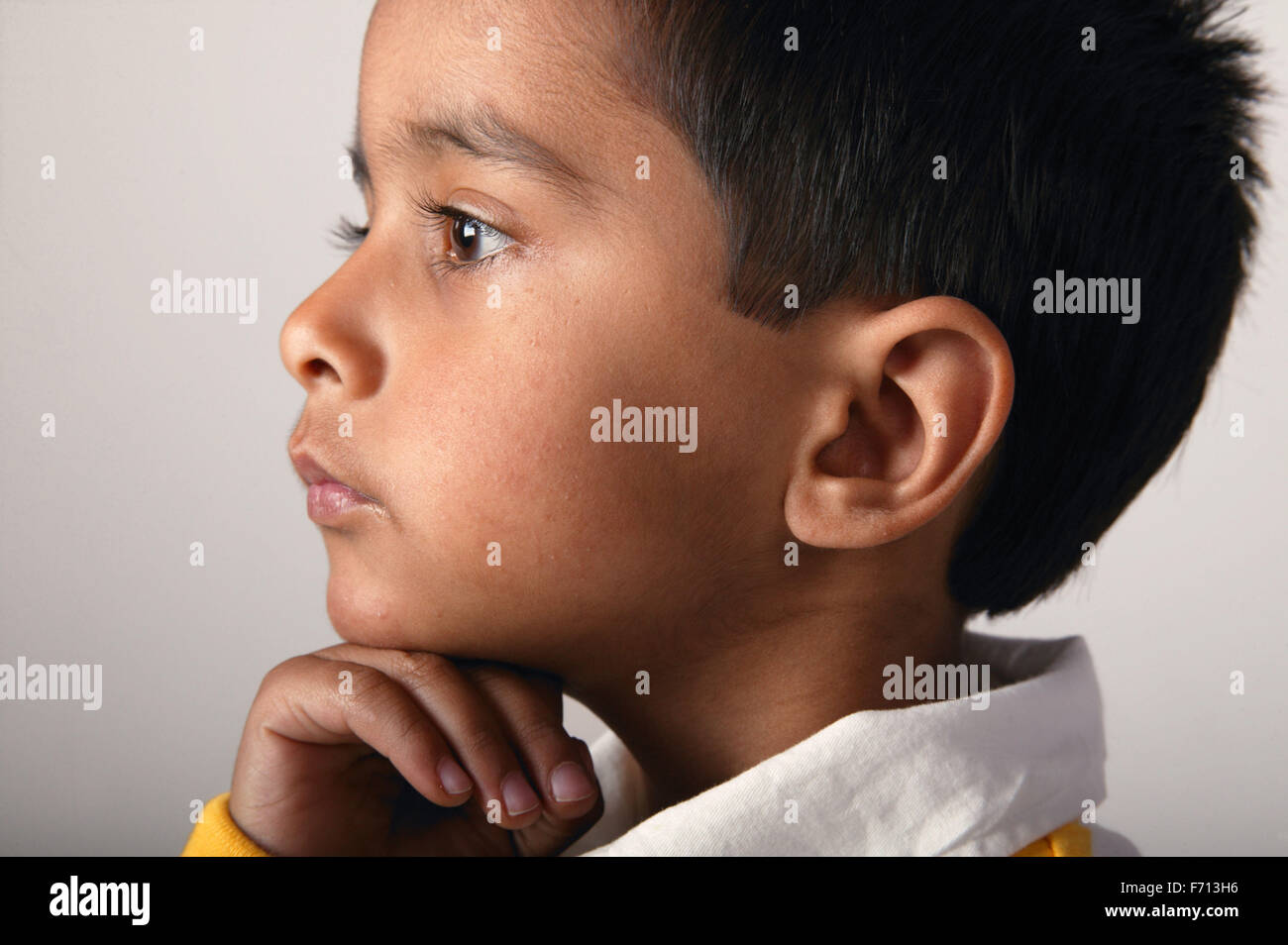 Profile of a young boy with hand under chin Stock Photo - Alamy
