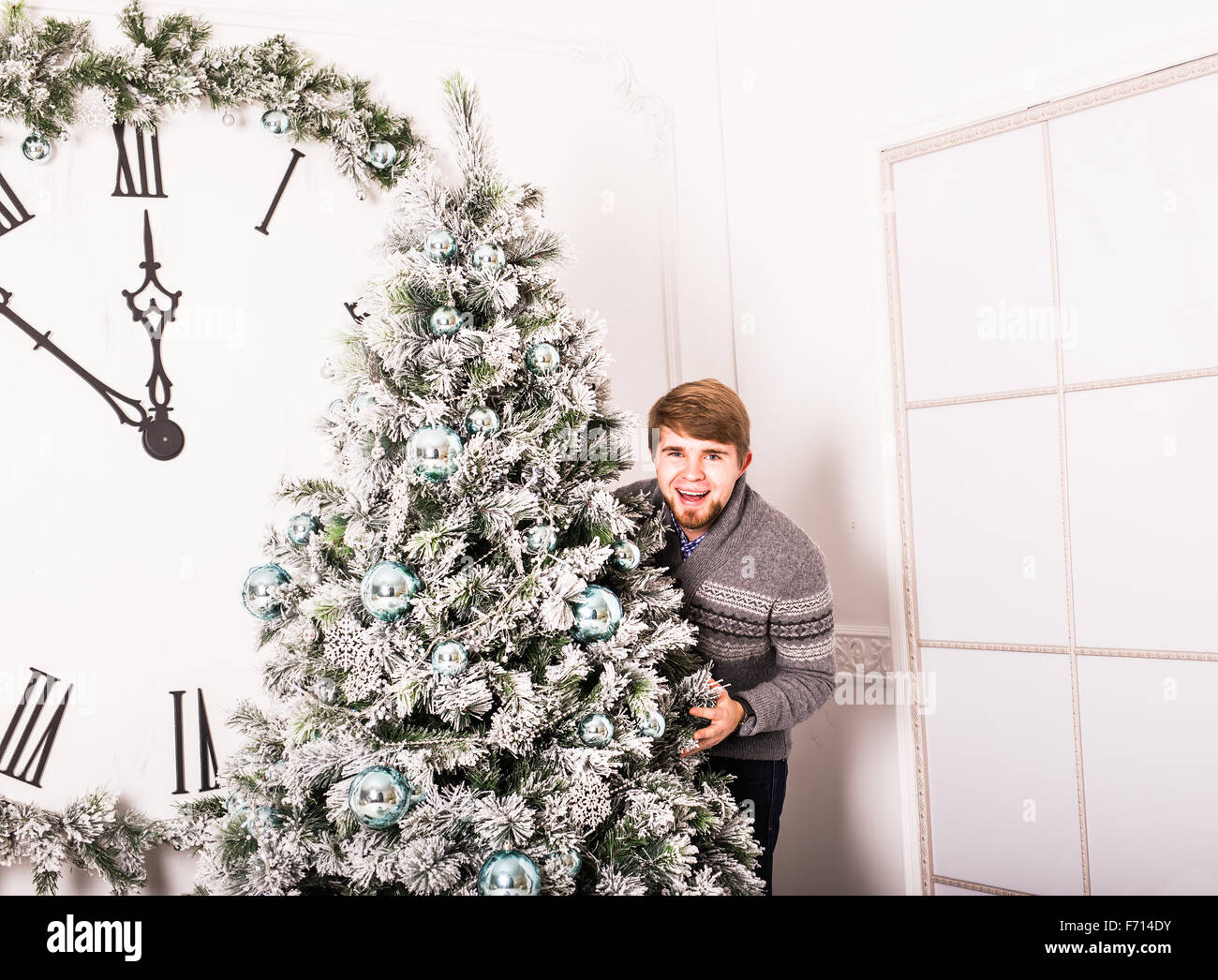 young man standing behind a Christmas tree Stock Photo - Alamy