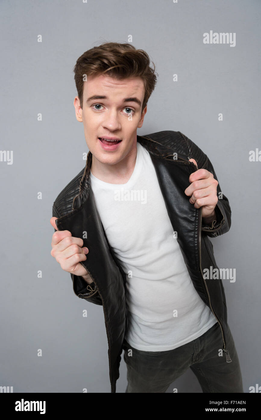 Portrait of a funny man in leather jacket standing over gray background ...