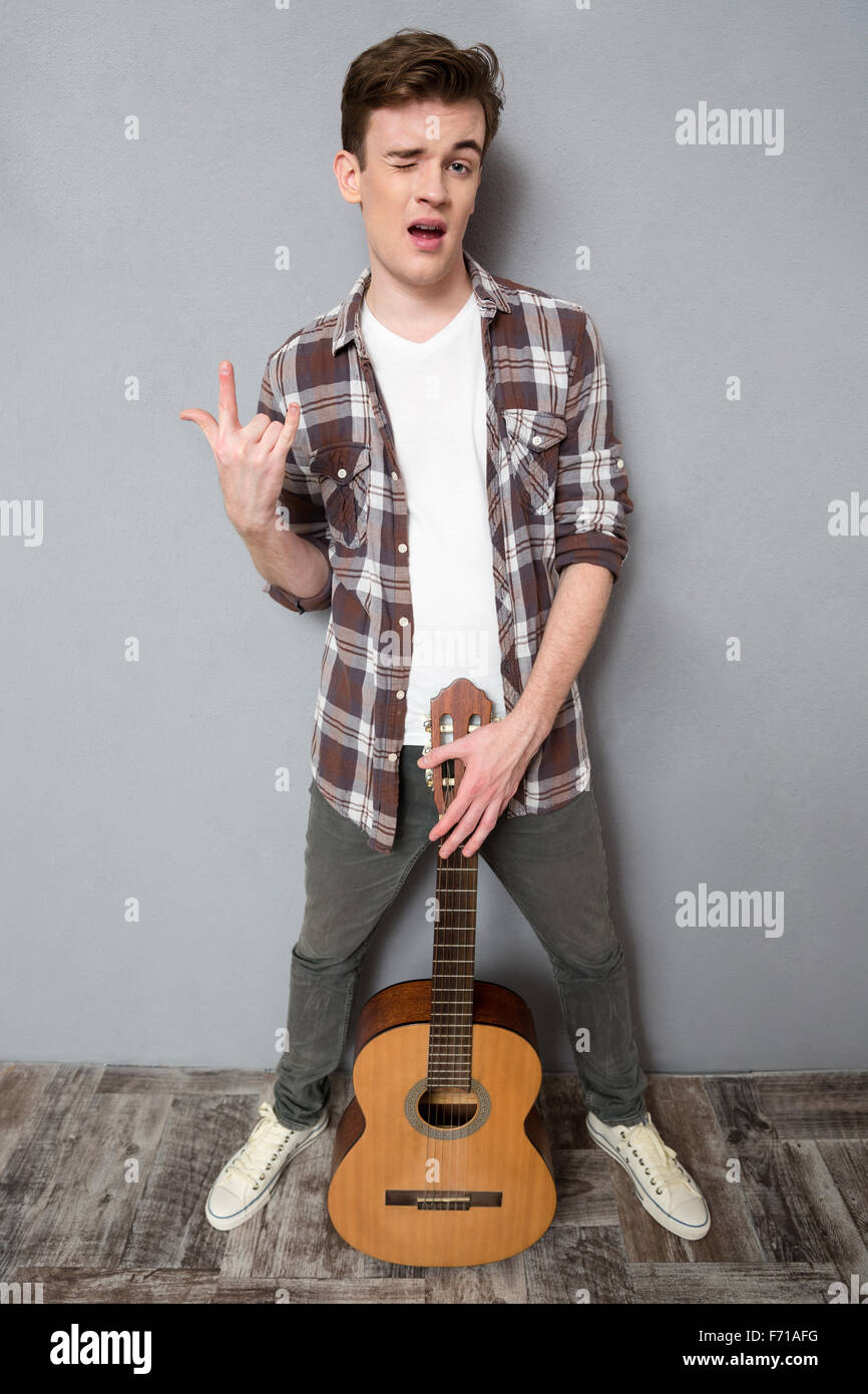 Portrait of a funny man standing with guitar on gray background Stock ...