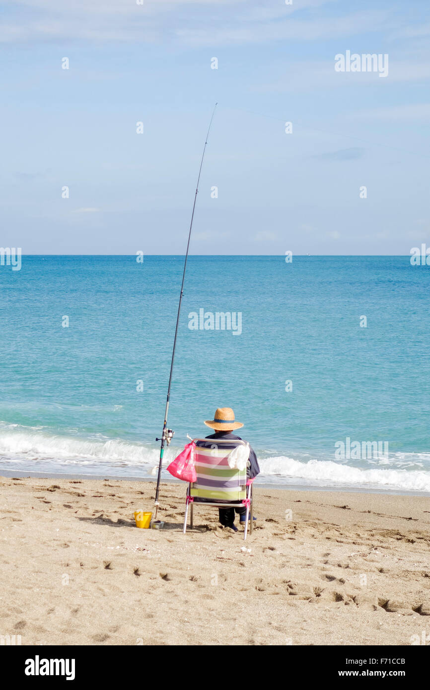 Fisherman Angler, alone angling on a mediterranean beach, fishing ...