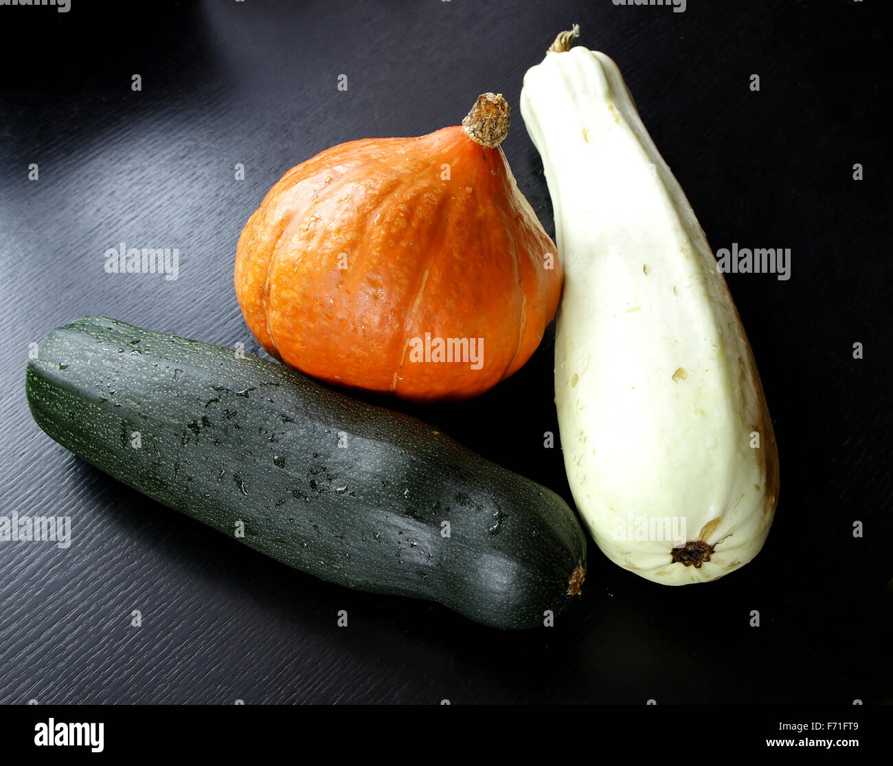 orange pumpkin and green squash vegetable marrow on black table Stock ...