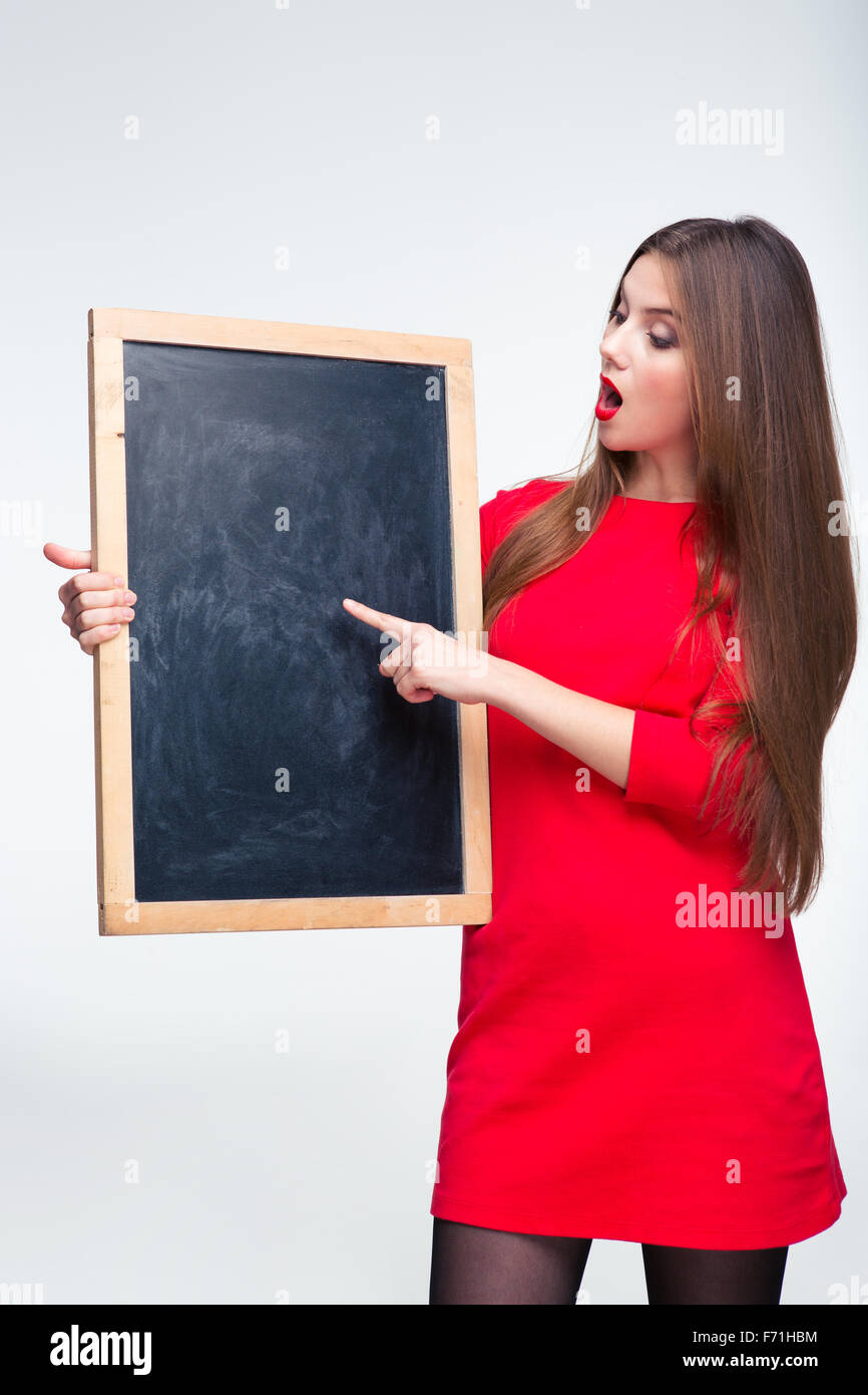 Portrait of a young woman in red dress pointing finger on blank board ...