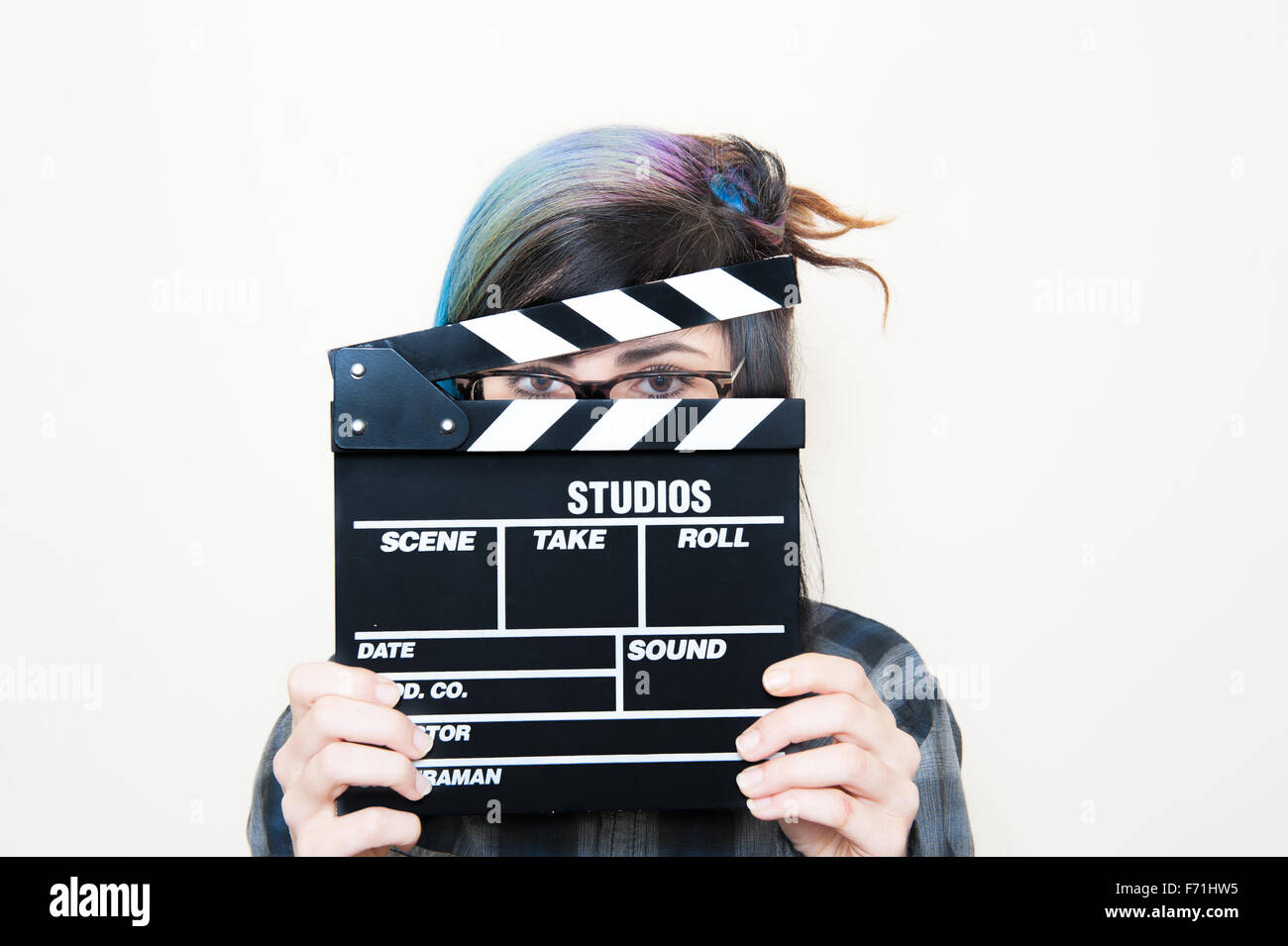 Young woman with clapper board on face and visible eyes on white ...