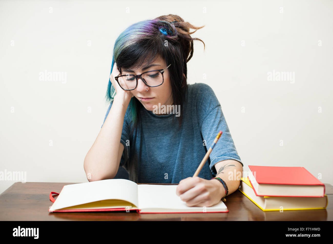 Young studying female student at desktop with red and yellow books ...